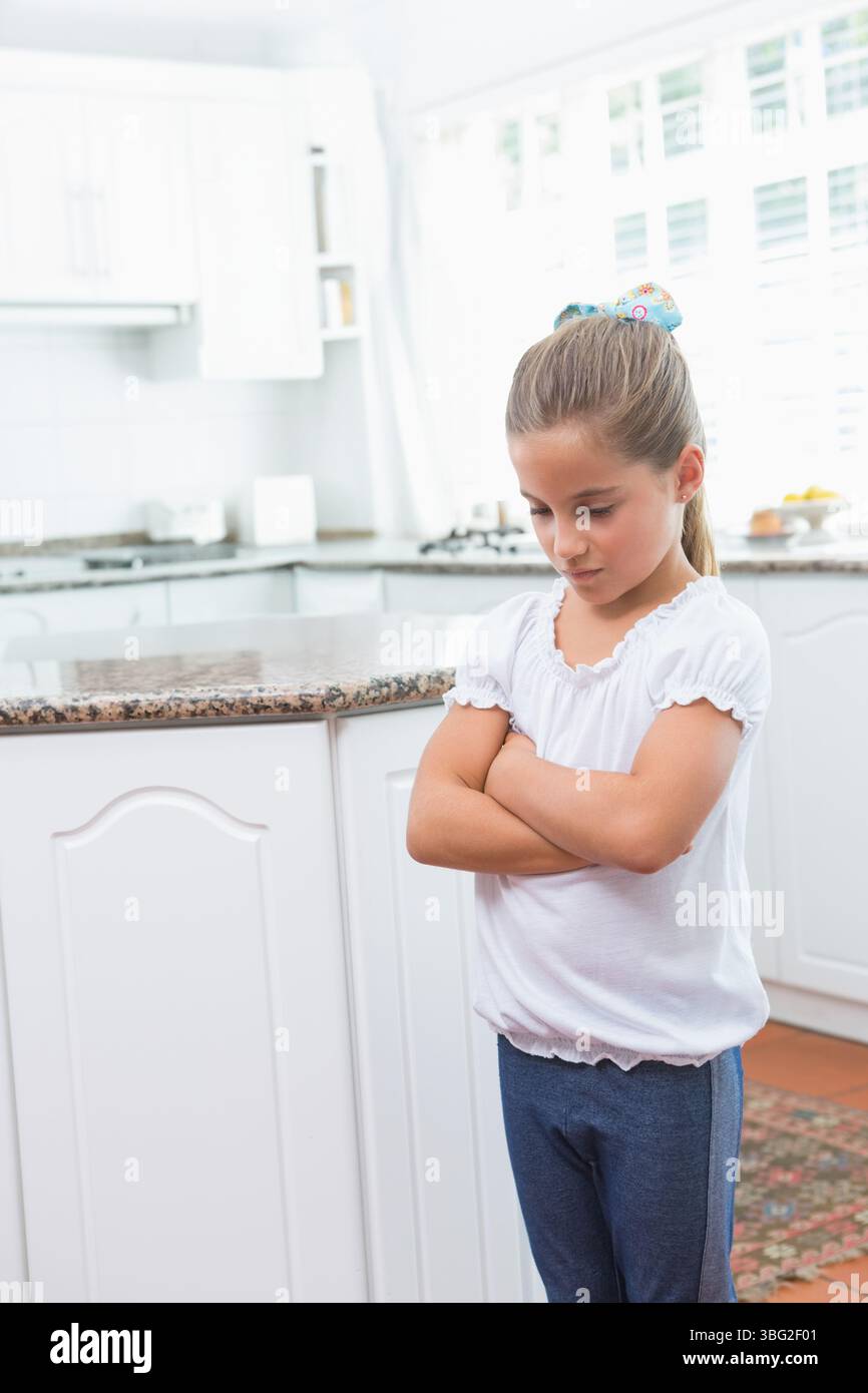 Female child folding arms across chest while standing in kitchen by ...
