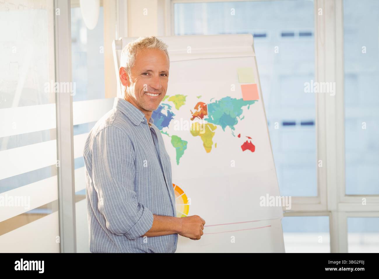 Middle-aged man presenting world map poster with sticky notes on flip ...