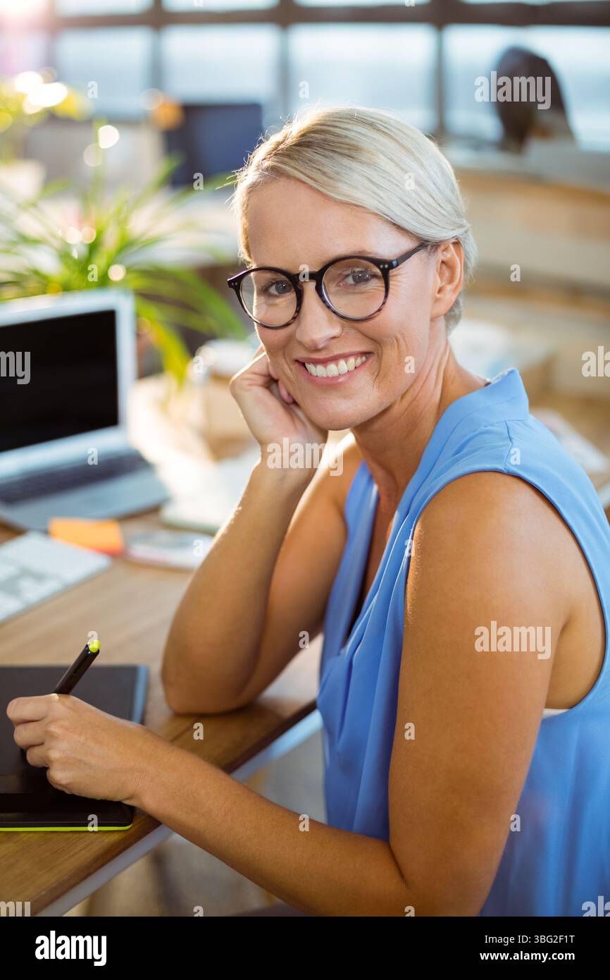 Female graphic designer using graphics tablet, leaning on cheek ...