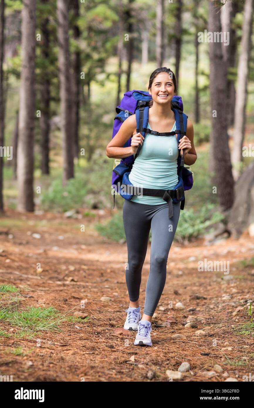 Female hiker in late twenties walking along conifer trail wearing ...