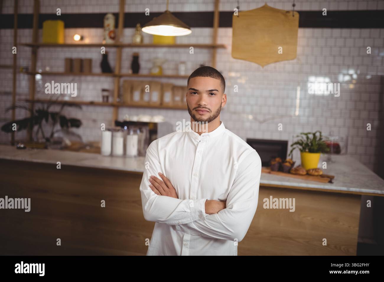 Man wearing white shirt standing behind marble-topped café counter with ...