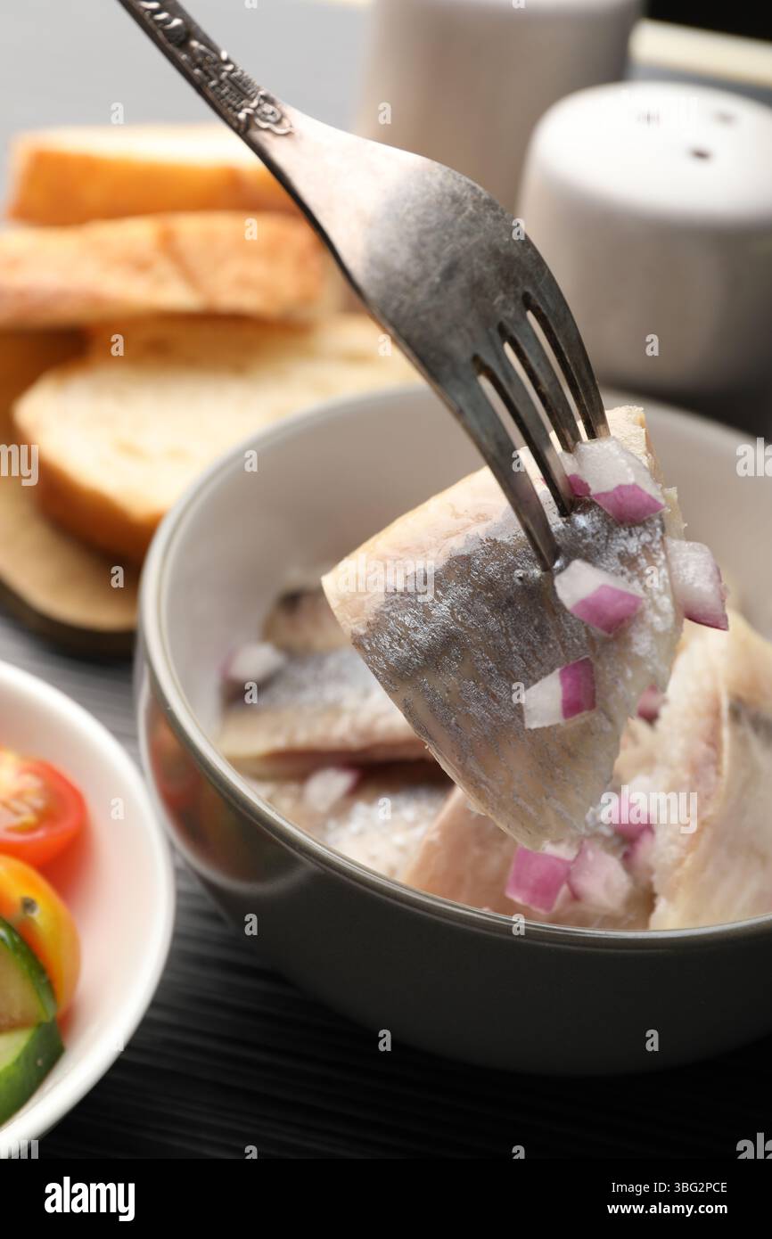 Eating delicious herring with onions at black table, closeup Stock ...