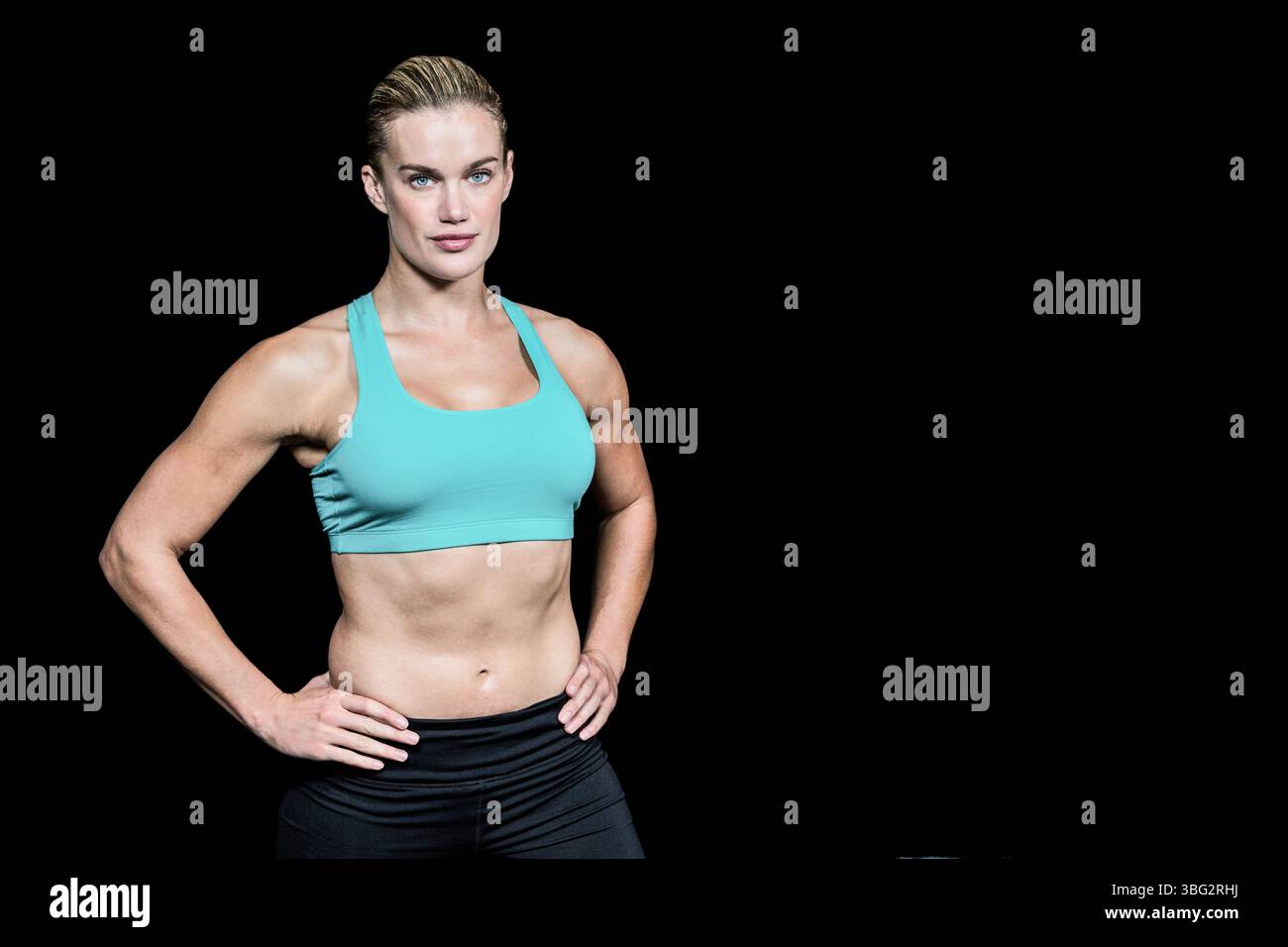 Adult female trainer in sportswear posing in studio against black wall ...