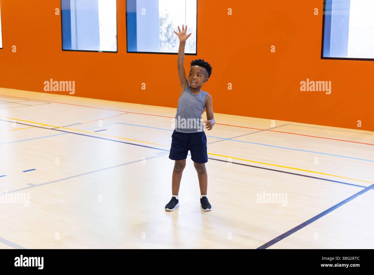 African American boy raising right arm while standing on multi-sport ...