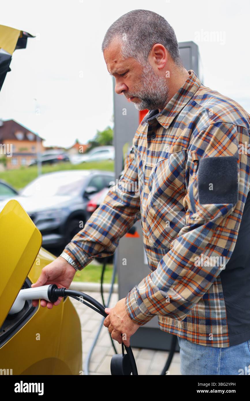 Man charging electric car at EV station. Eco-friendly transportation ...
