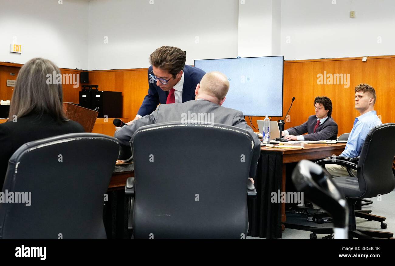 Defense attorney Anthony Cotton, center standing, confers with ...