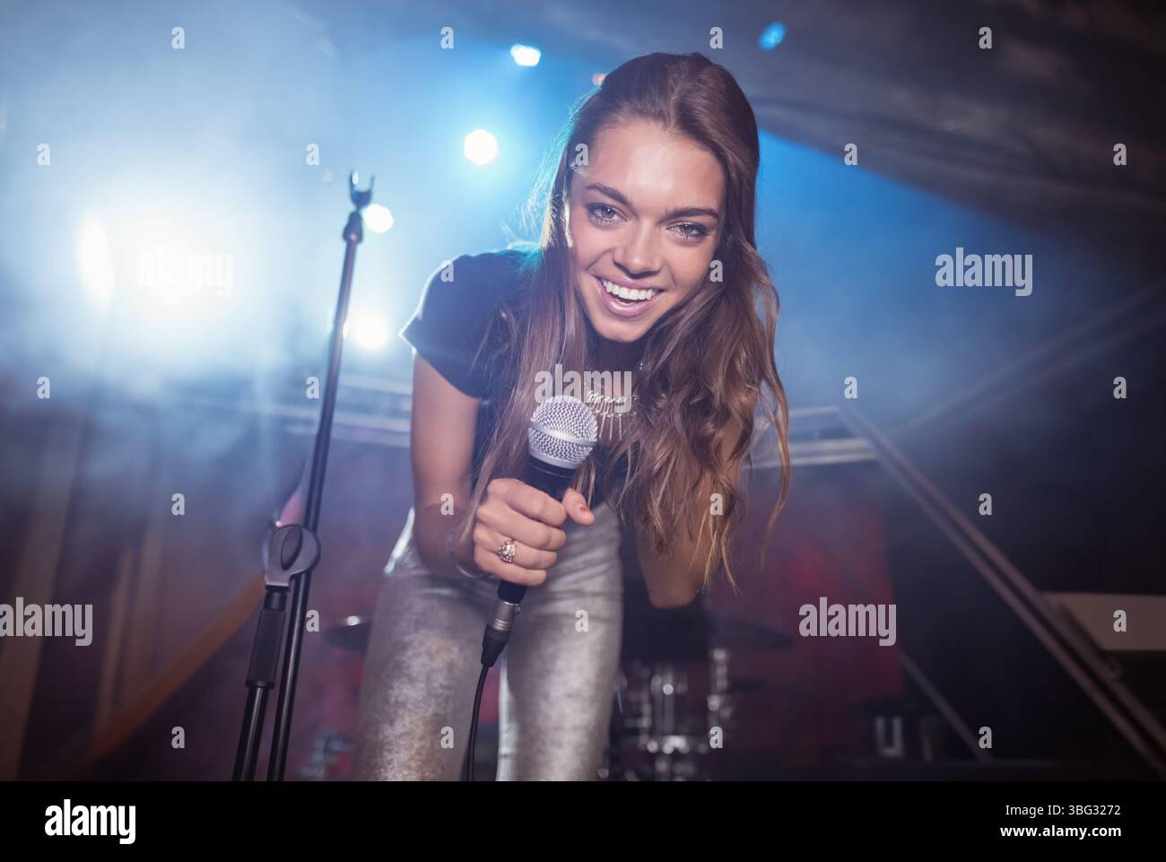 Female singer performing on stage leaning toward audience holding ...