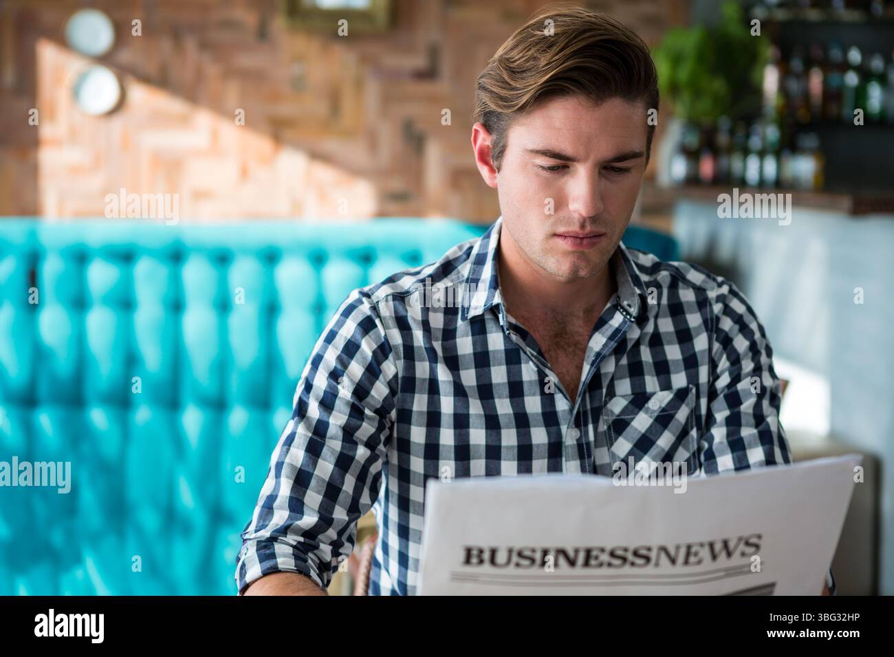 Man sitting in cafe booth reading BUSINESSNEWS newspaper with tufted ...