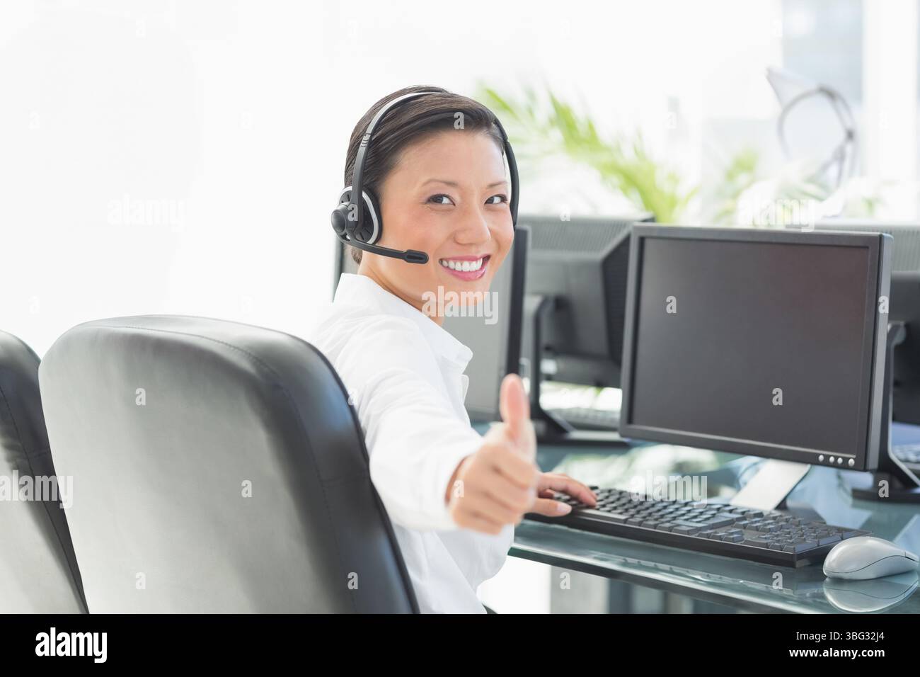 Headset resting on black leather chair at glass desk with monitors ...