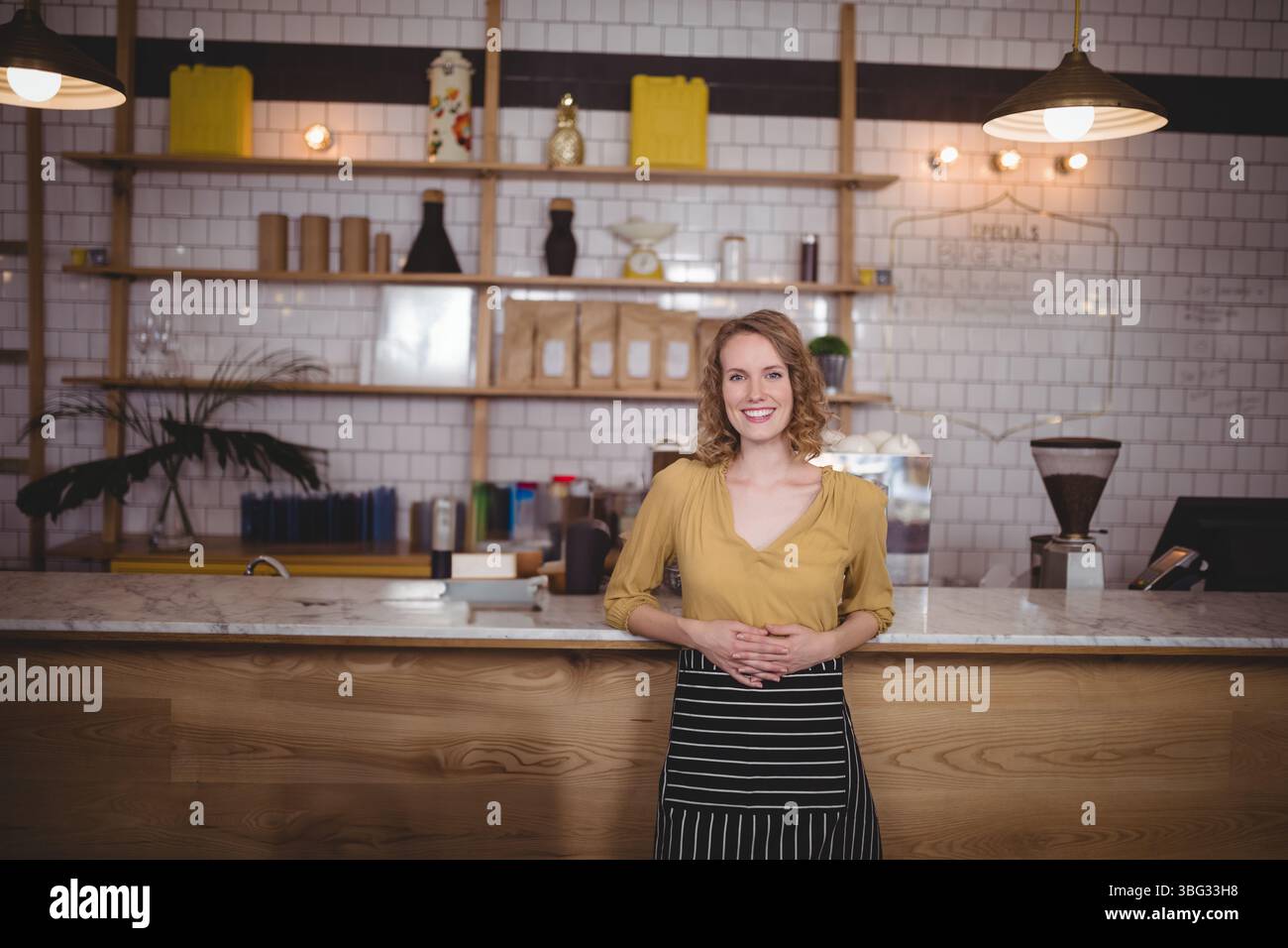 Woman barista wearing mustard blouse and apron operating espresso ...