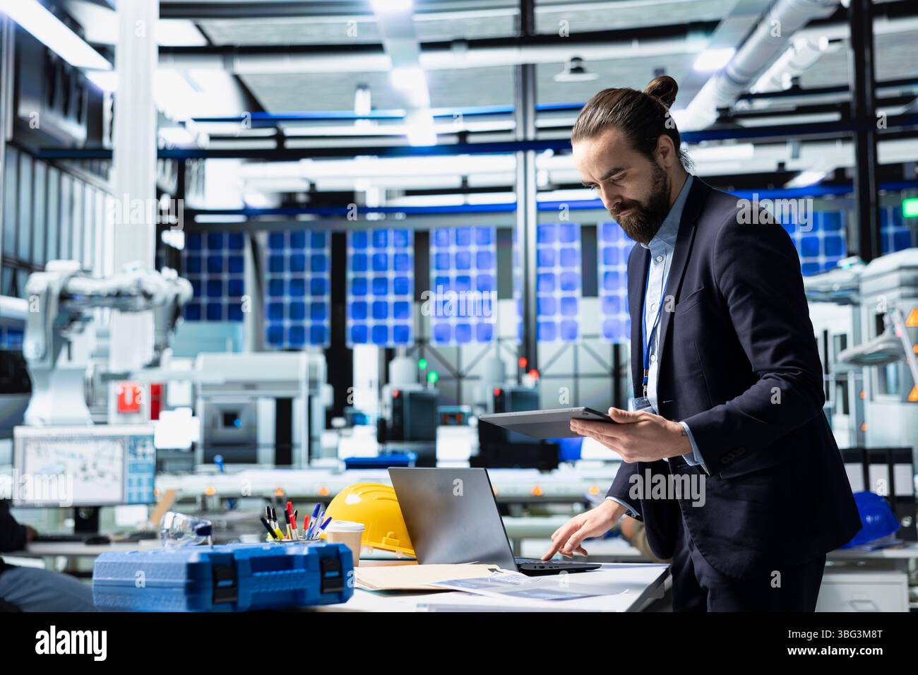 Solar energy specialist in a facility reviews data on gadget ...