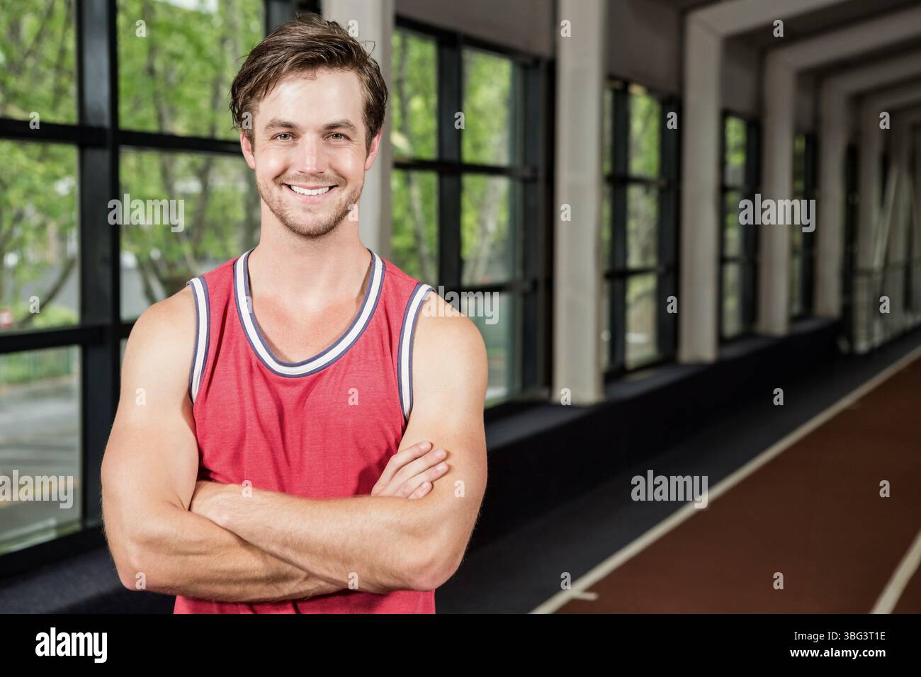 Male athlete standing inside gym by windows and support columns wearing ...