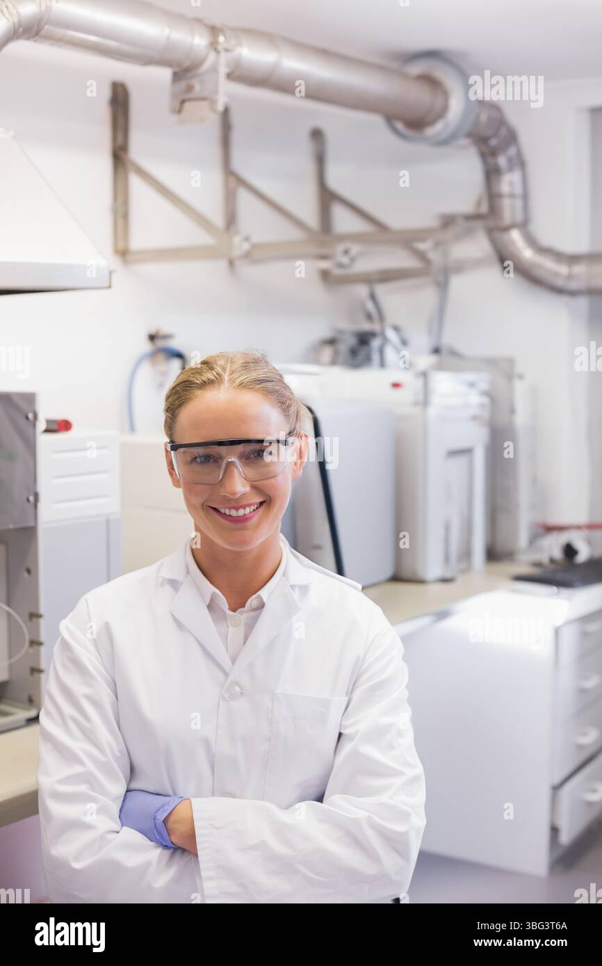 Female lab technician wearing lab coat and gloves operating analytical instruments at lab bench ...
