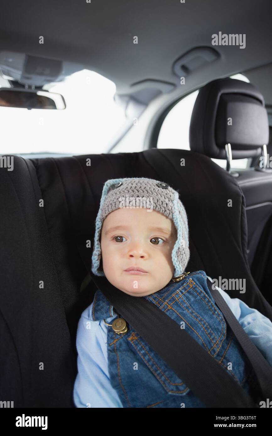 Male toddler sitting in car child safety seat wearing grey hat and ...
