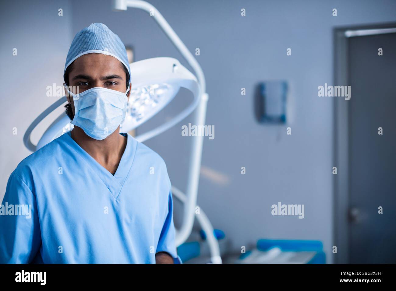 Asian male surgeon standing under overhead lamp in surgery room by ...