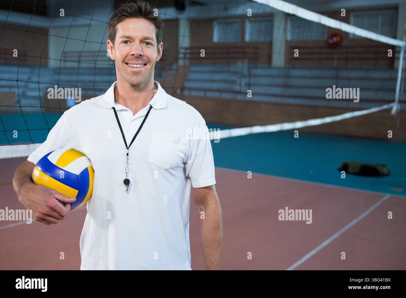 Male volleyball coach holding volleyball wearing whistle on court with ...
