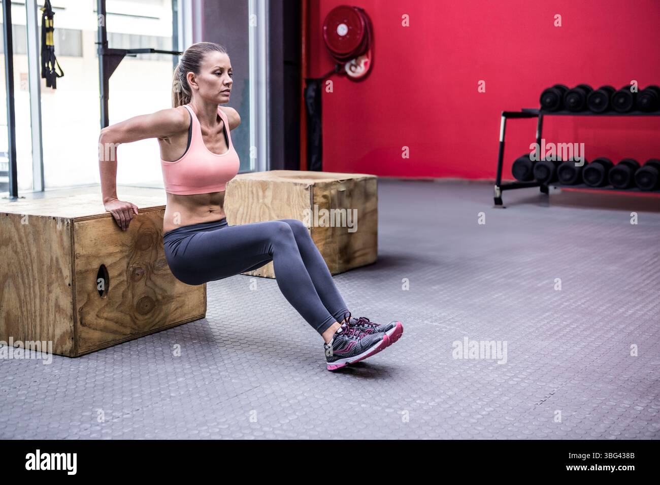 Woman in sportswear performing triceps dip gripping wooden boxes under ...