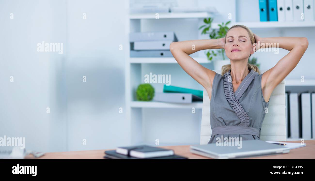 Senior woman in business attire leaning back at desk with laptop ...