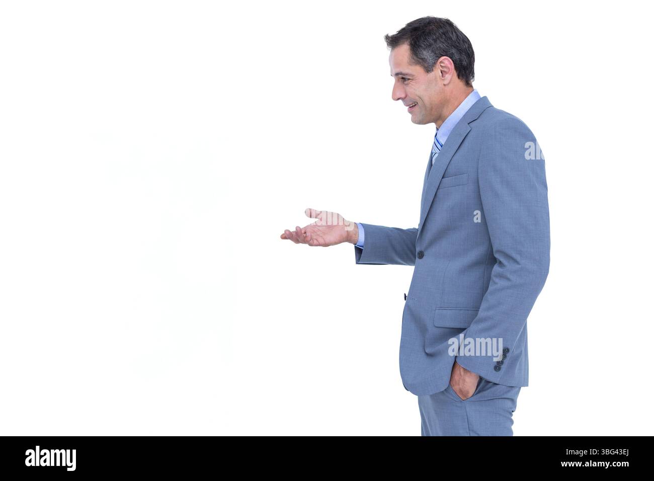 Mature man in blue suit standing in profile, gesturing with palm up in ...