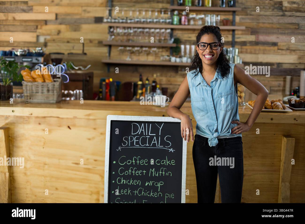 Smiling African American woman leaning behind coffee shop counter with ...