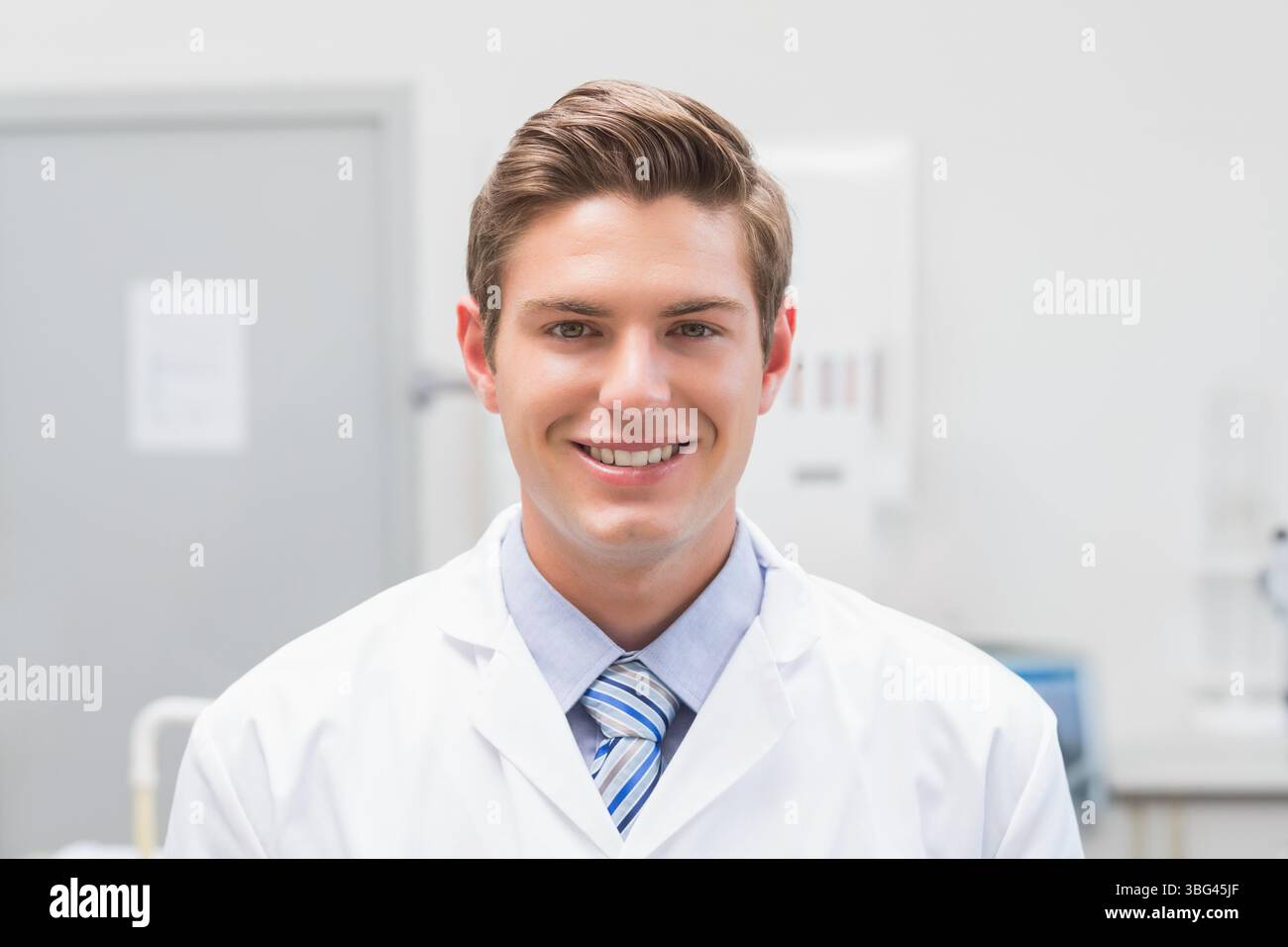Male doctor smiling while wearing white lab coat and striped tie in ...