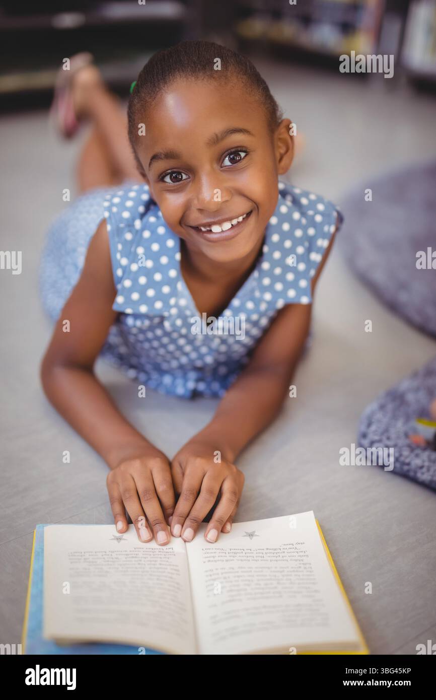 African American child girl lying on floor in living area reading book ...
