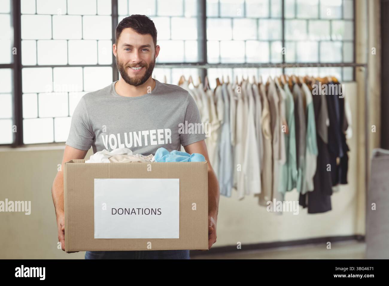 Male volunteer standing in sorting room holding donation box near ...