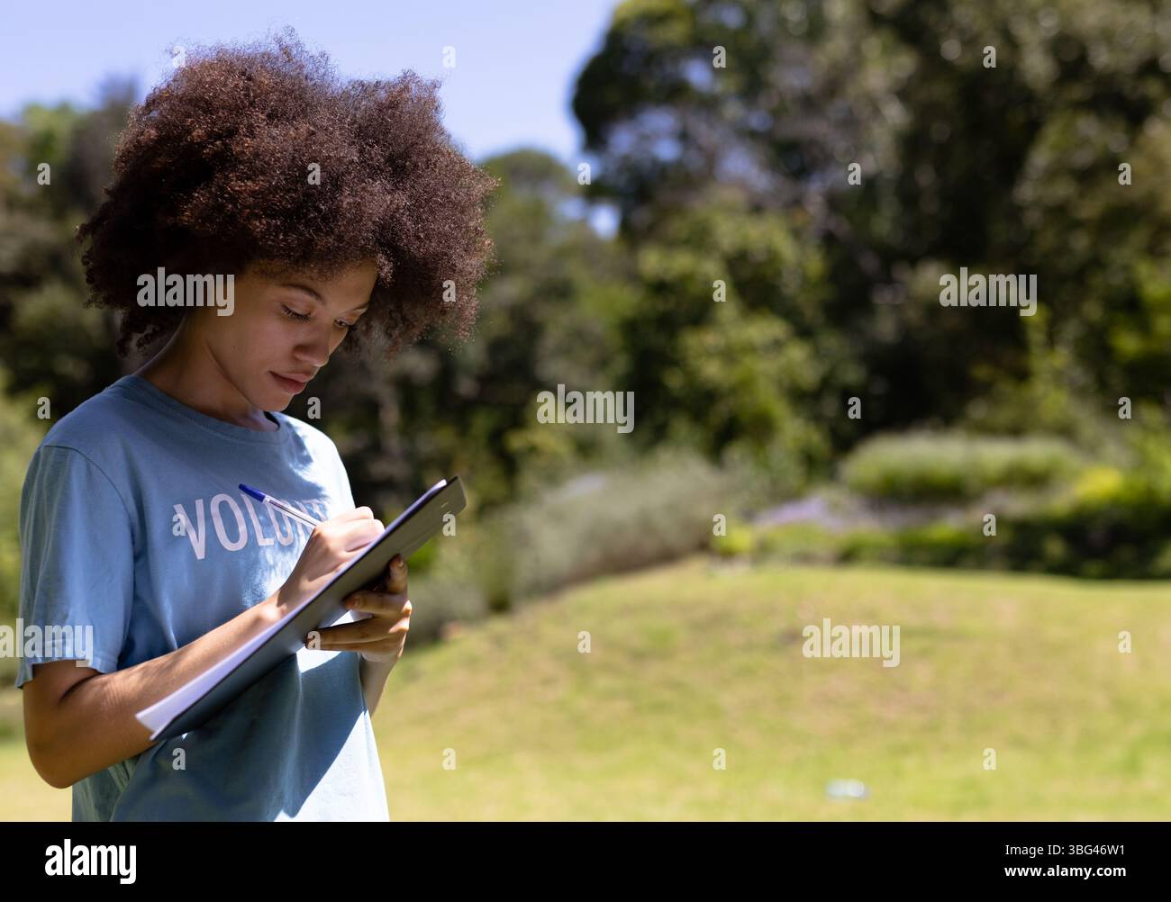 African American female volunteer jotting notes on clipboard with pen ...