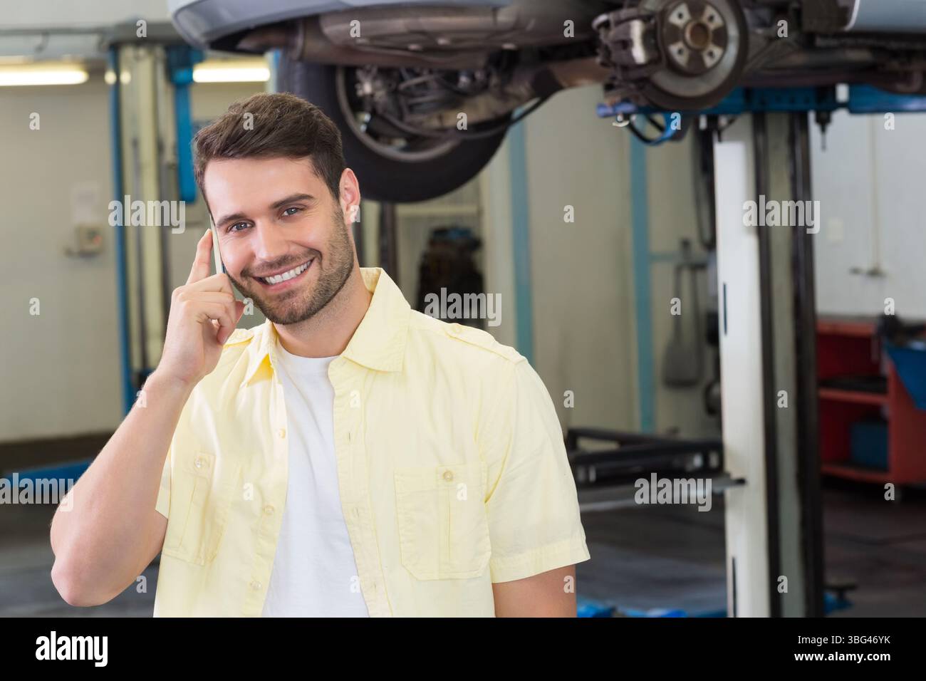 Man smiling and touching temple in automotive repair shop beside ...