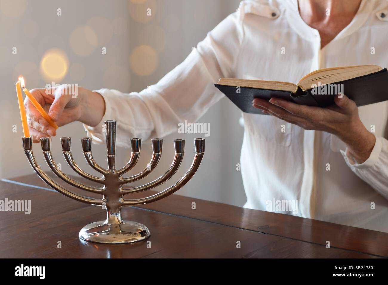 Woman lighting first candle of Chanukah on Menorah with the shamash ...