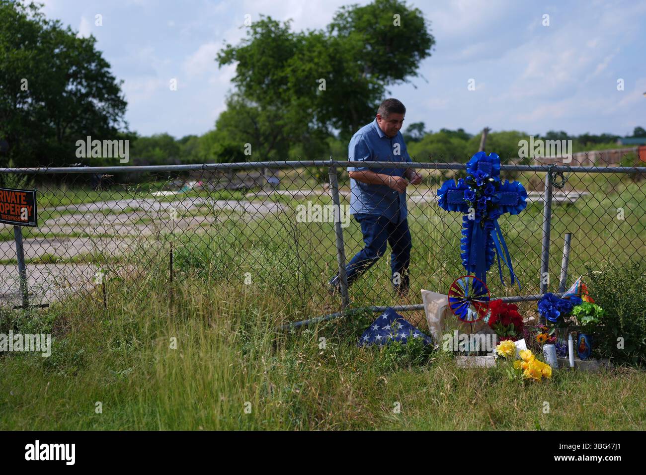 Adriane Reyes adds a cross to candles, flowers, and notes that create a ...