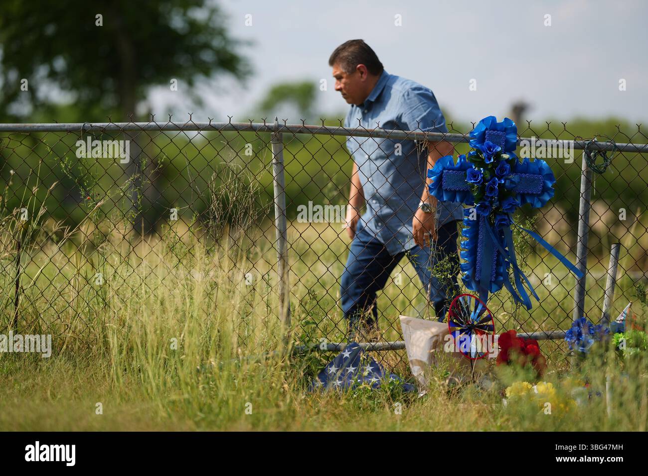 Adriane Reyes adds a cross to candles, flowers, and notes that create a ...