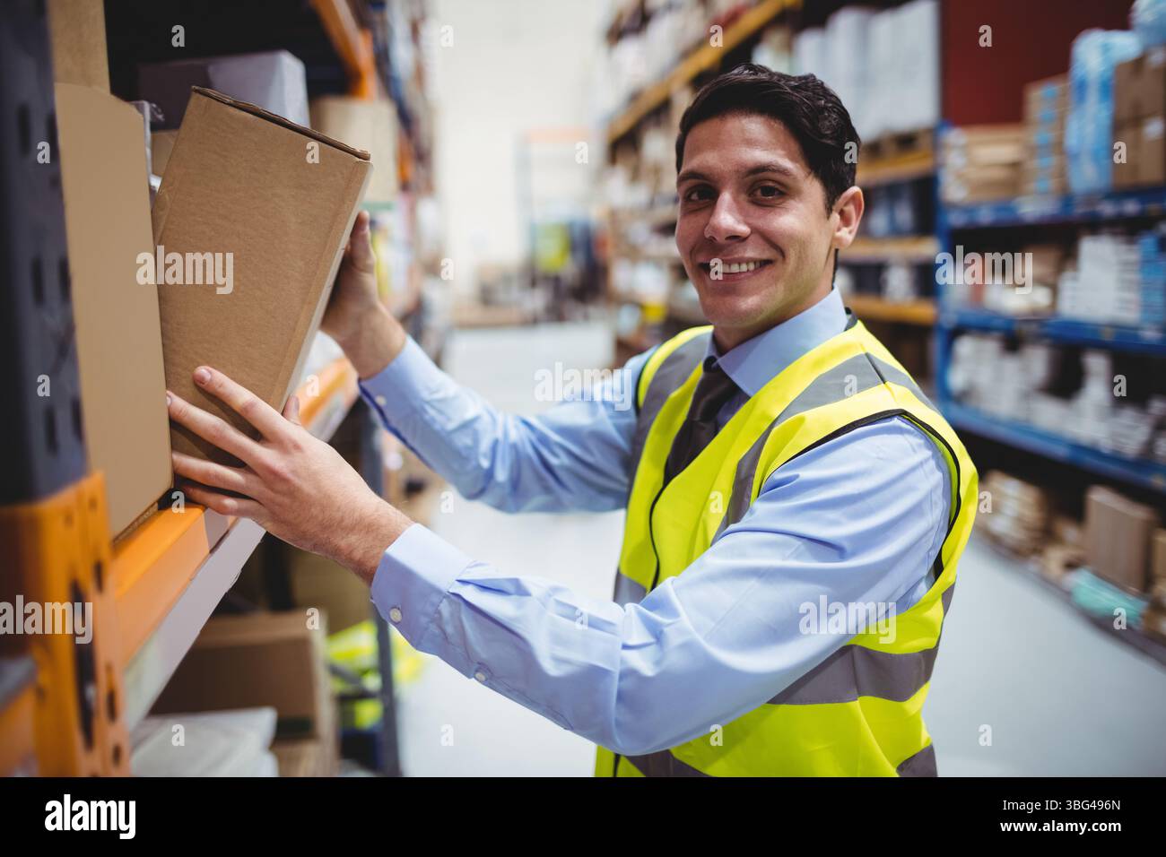 Man standing in warehouse aisle wearing hi-vis safety vest holding ...