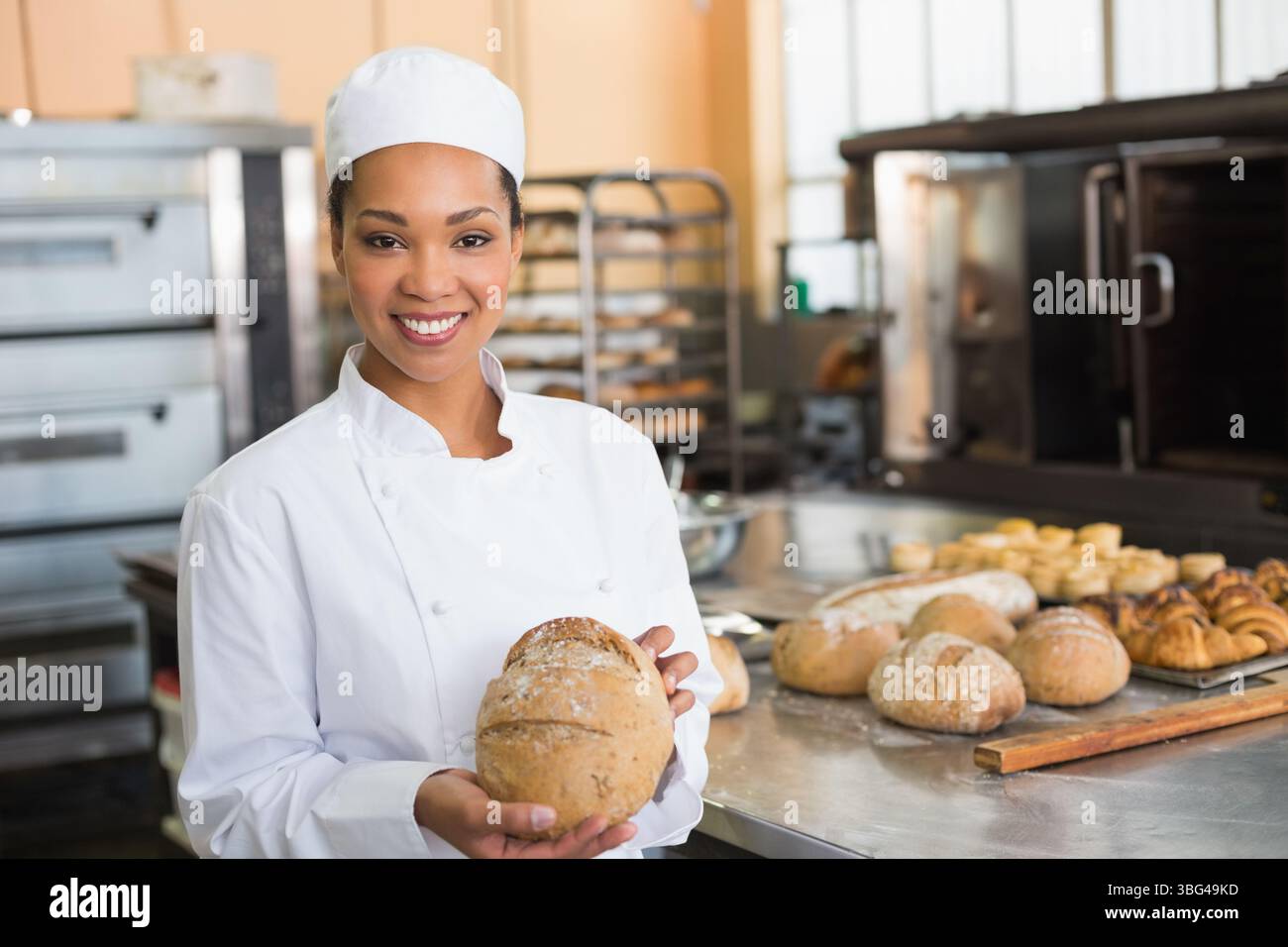 African American woman wearing chef coat and baker cap holding round ...