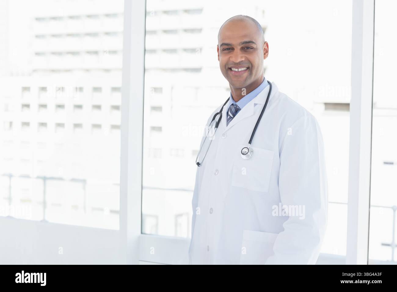 Doctor standing near large window in bright medical facility, with ...
