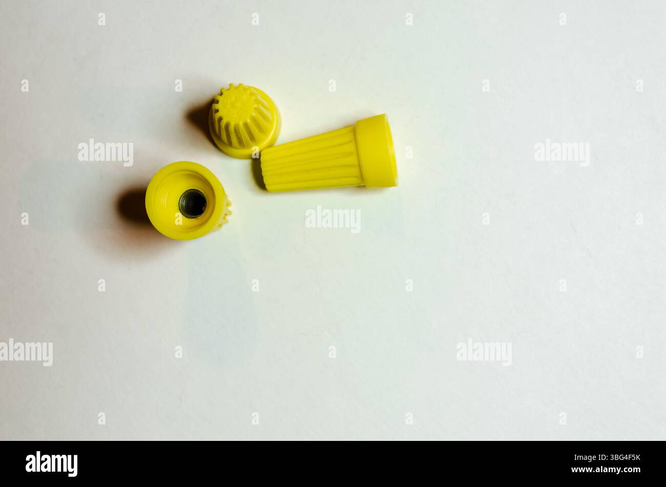 three yellow wire twist connectors on a white background, one showing ...