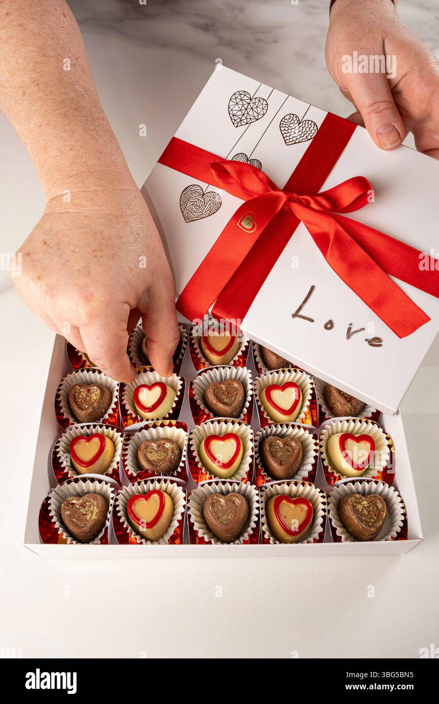 Woman taking a chocolate from a box with a red bow top view Stock Photo ...