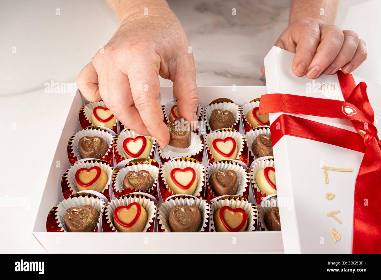 Woman taking an assorted chocolate from a white box Stock Photo - Alamy