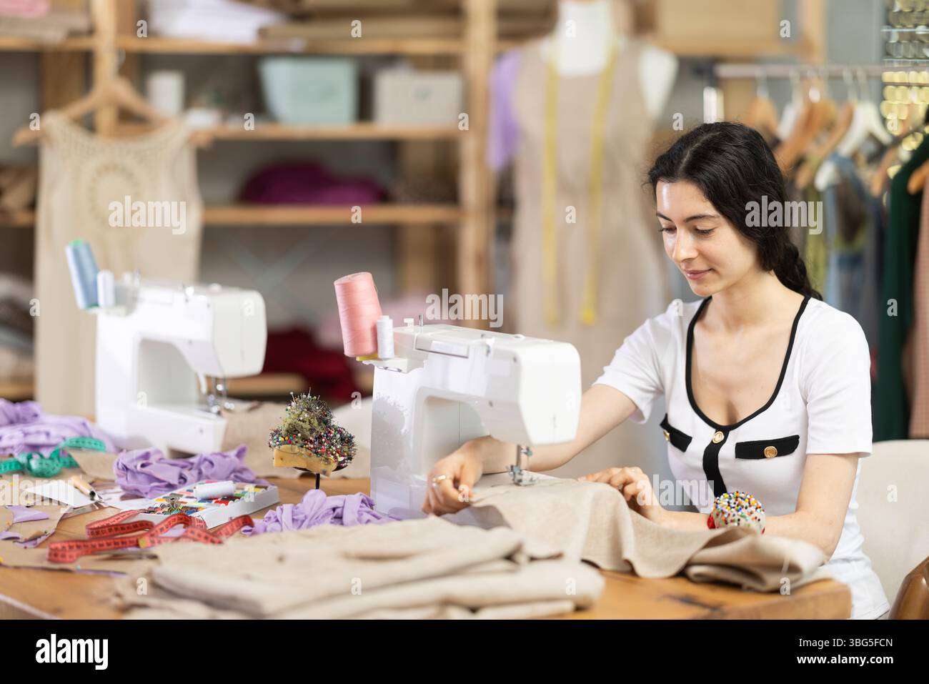 Female tailor using sewing machine to make garment in studio Stock ...