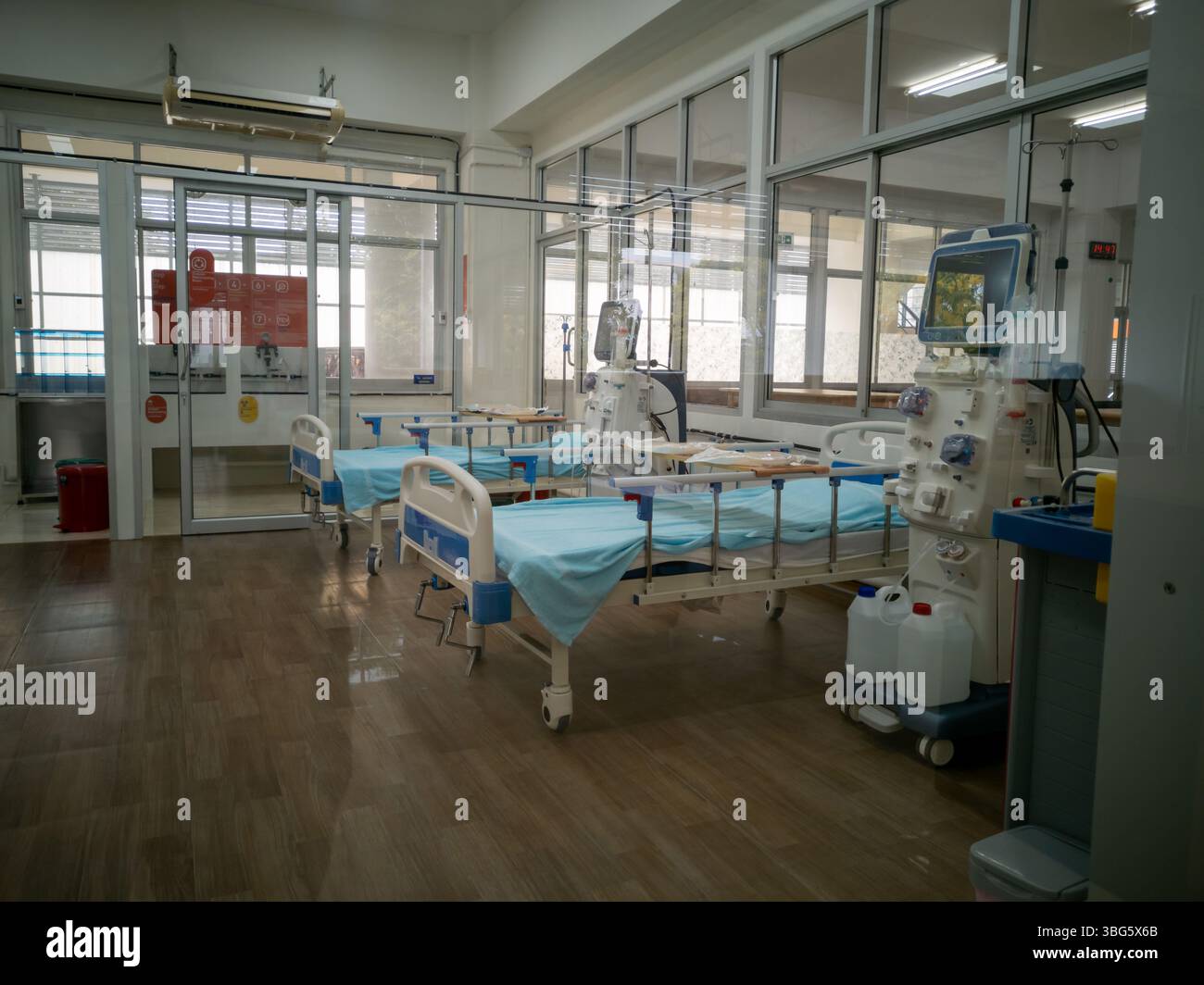 This image shows a well-lit hospital room featuring empty beds and ...