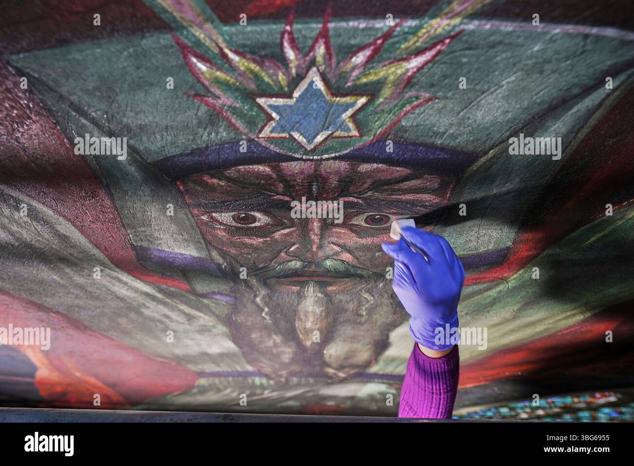 Art conservator Naomi Ruiz works on the face of Moses as depicted in a ...