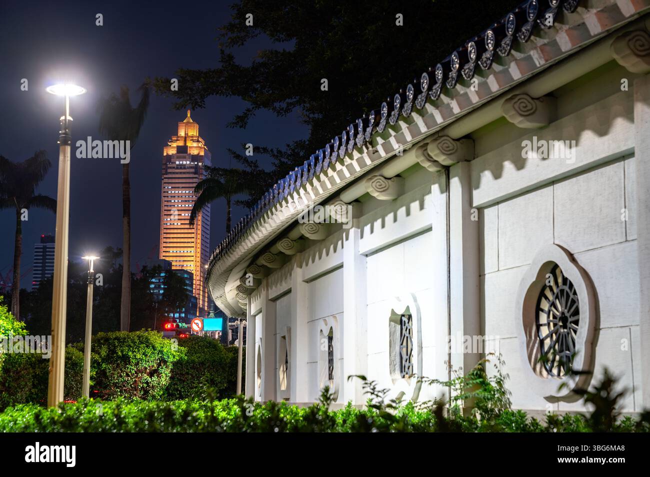 In Taipei, Taiwan, an illuminated skyscraper rises over the white tiled ...