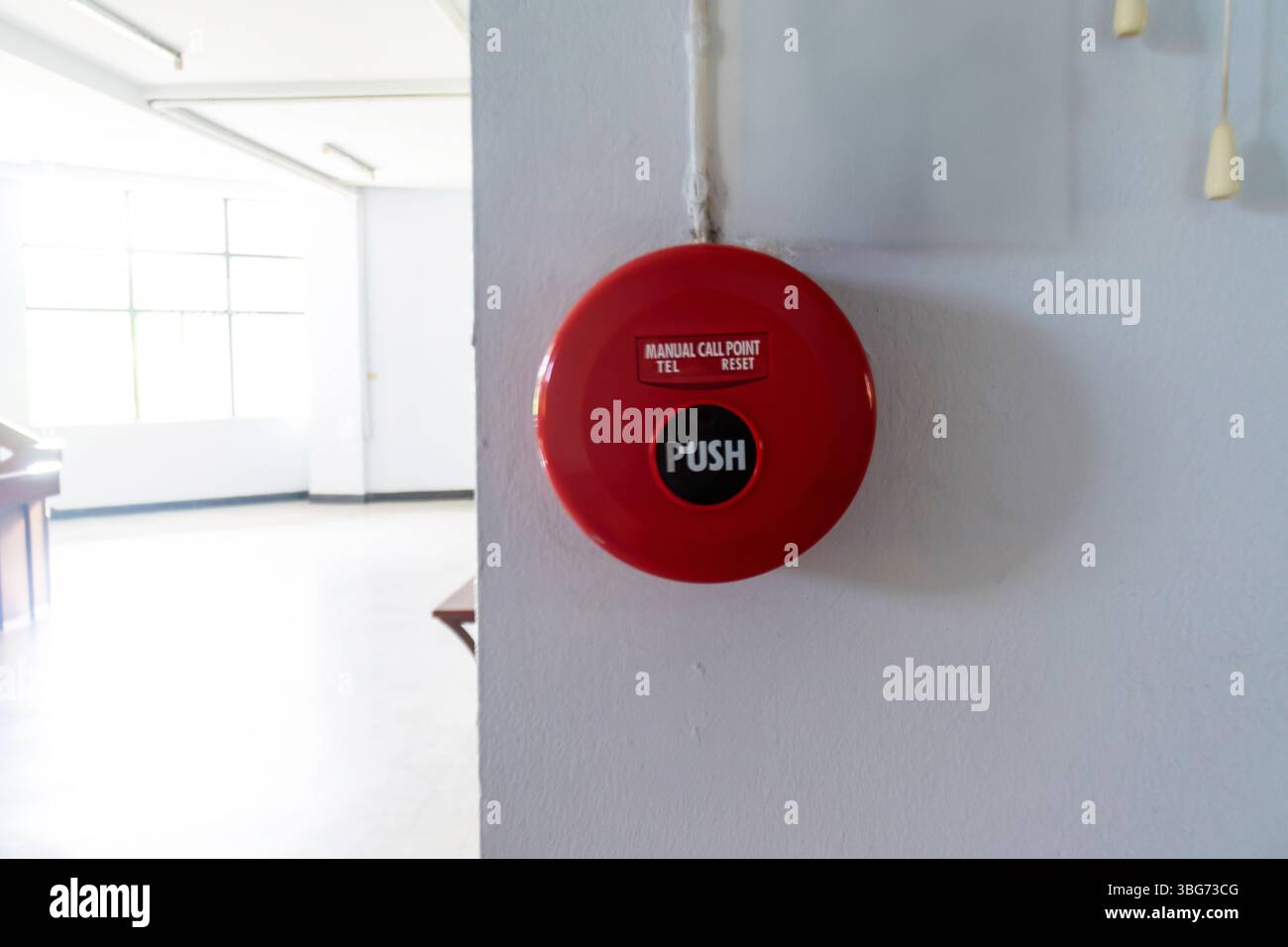 A striking red emergency alarm button mounted on a wall, designed to ...