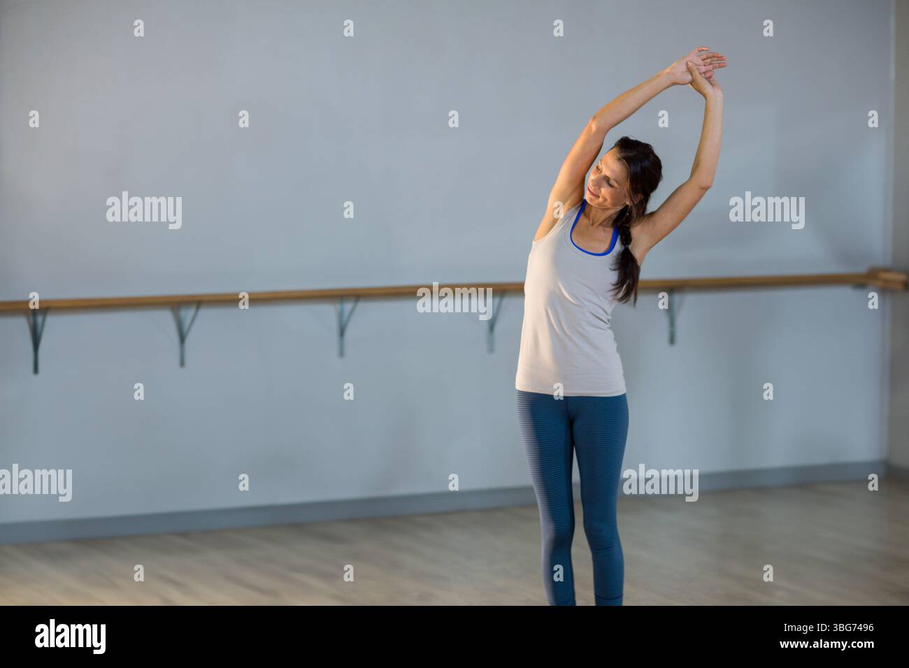 Asian woman stretching arms overhead and leaning sideways in dance ...