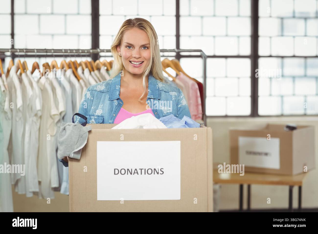 Female volunteer holding cardboard box labeled DONATIONS at donation ...