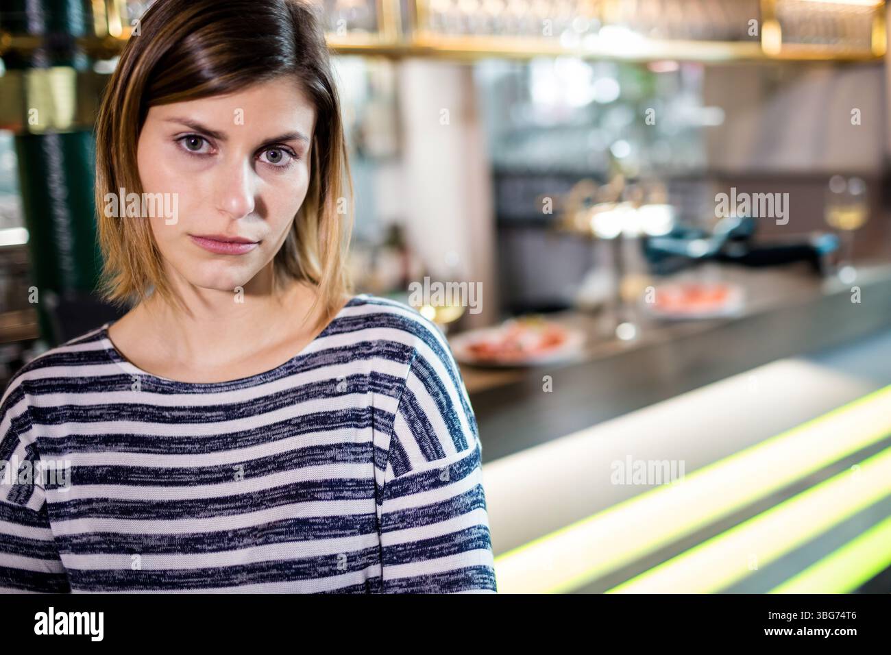 Woman standing by bar counter in cozy bar with illuminated panels and brass taps, copy space ...