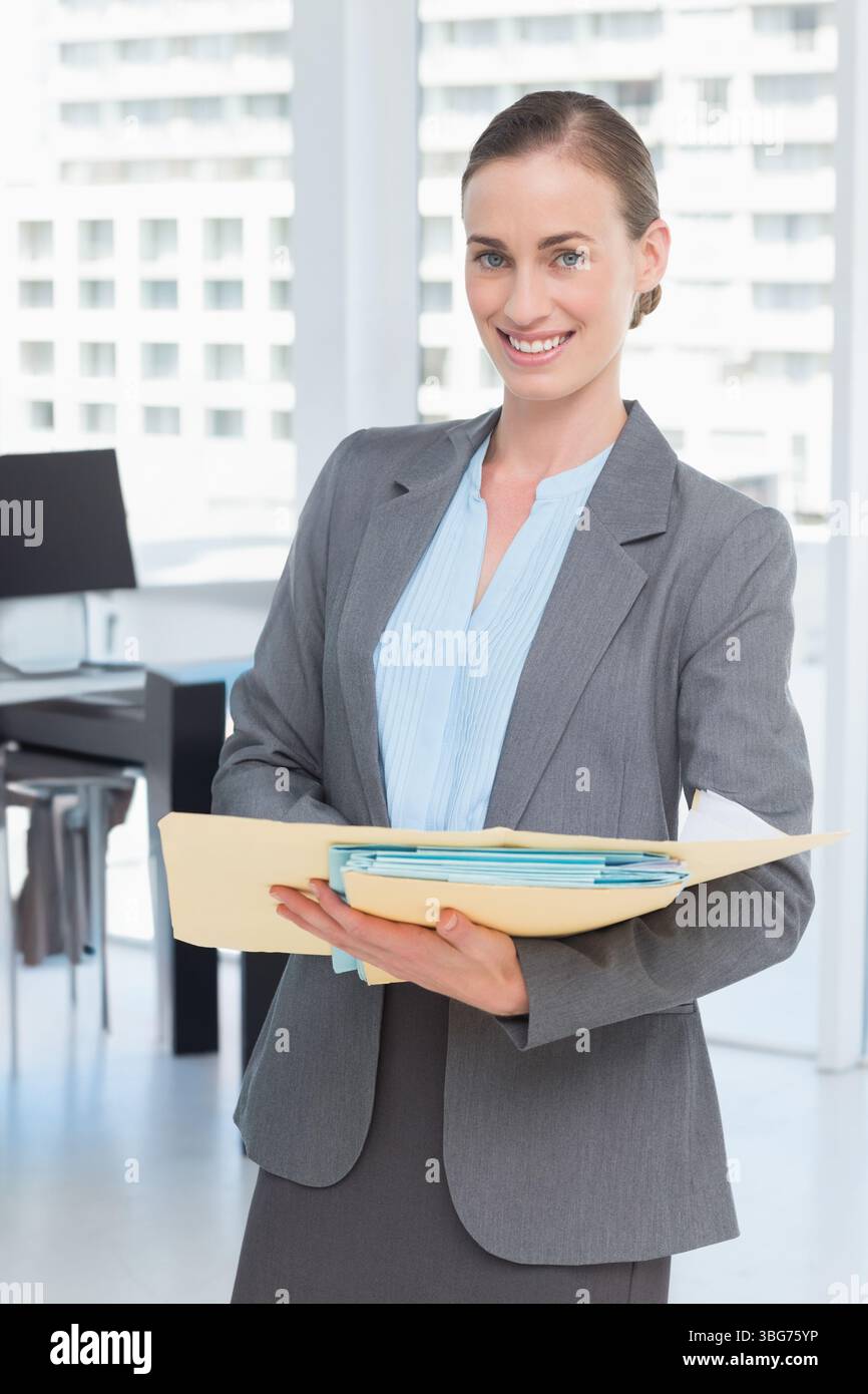 Female professional standing in modern office holding papers in manila ...