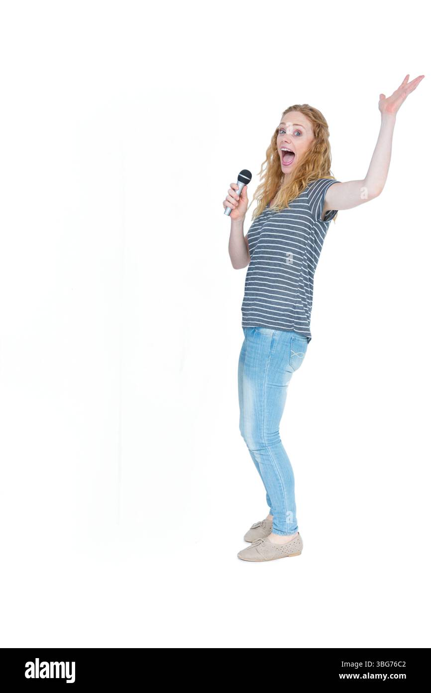 Woman standing in studio wearing striped shirt holding handheld mic ...