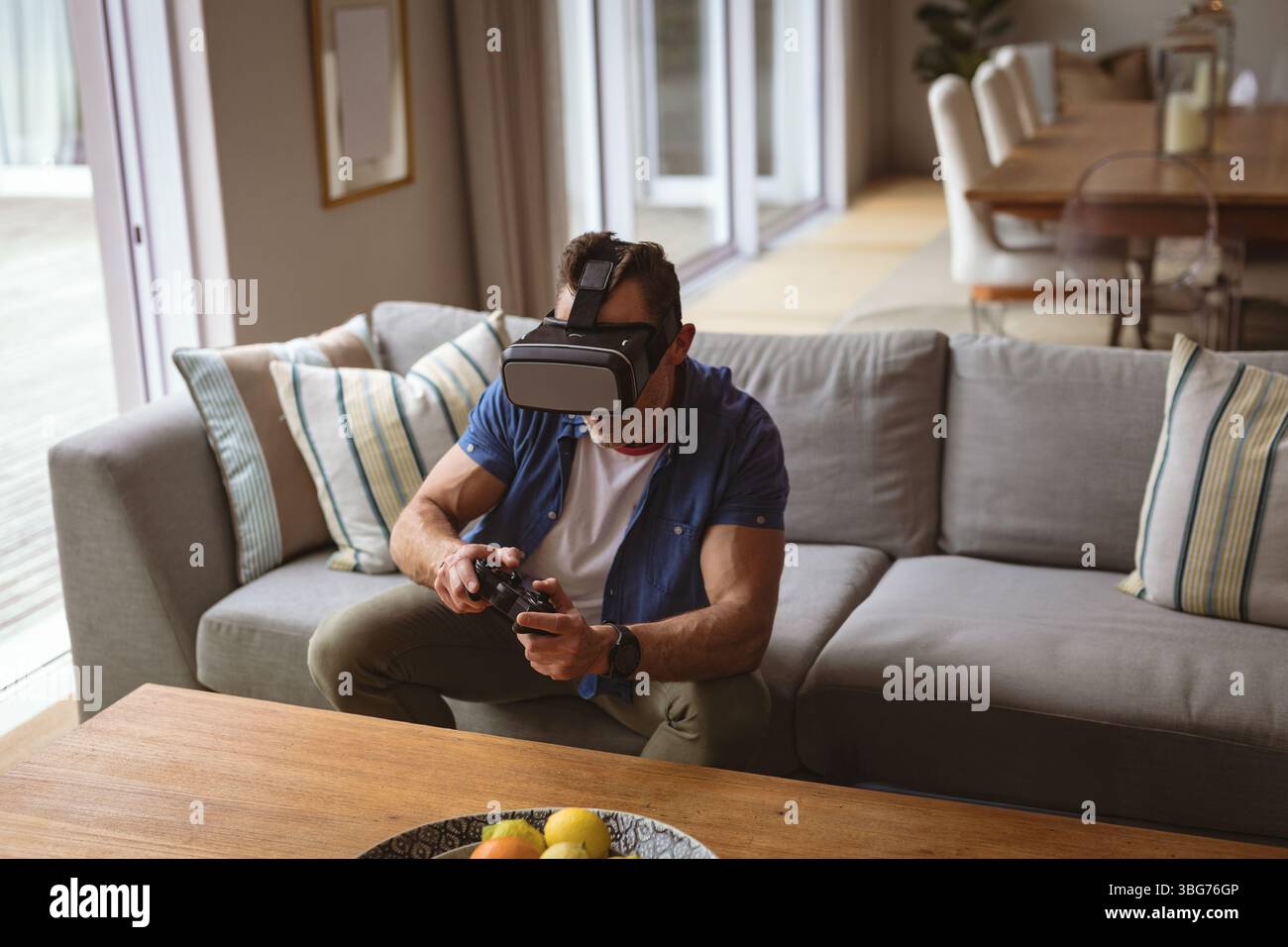 Virtual reality headset displaying game scene on gray sofa in modern ...