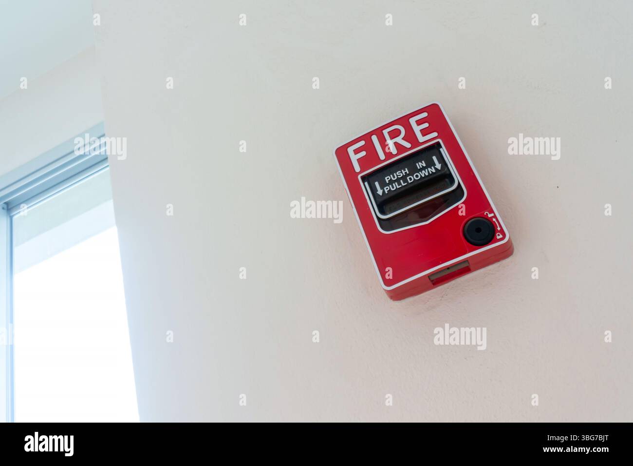 Bright red fire alarm box mounted on a white wall, designed for ...
